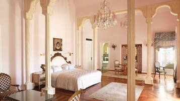 Um quarto espaçoso com uma cama grande, uma mesa de vidro e um candelabro.