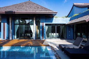 Uma casa moderna com piscina, portas de vidro grandes e móveis de exterior.