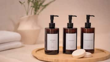 Três frascos de gel de banho, shampoo e condicionador sobre um tabuleiro de madeira.