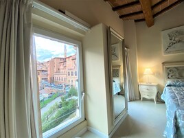 Quarto com uma janela grande, uma cama, uma mesa de cabeceira e um espelho.