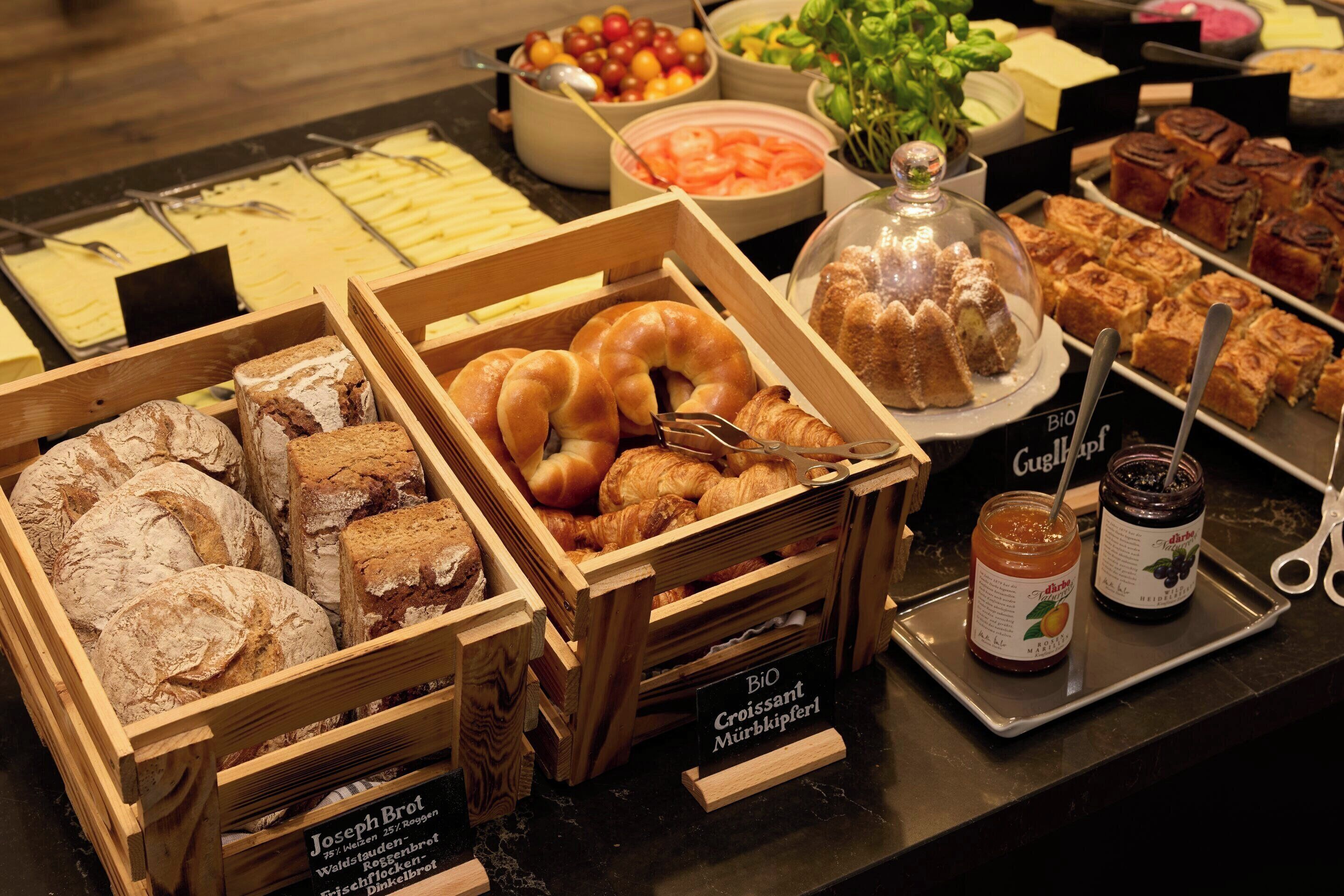 Buffet com diversos alimentos, incluindo pão, doces e acompanhamentos.