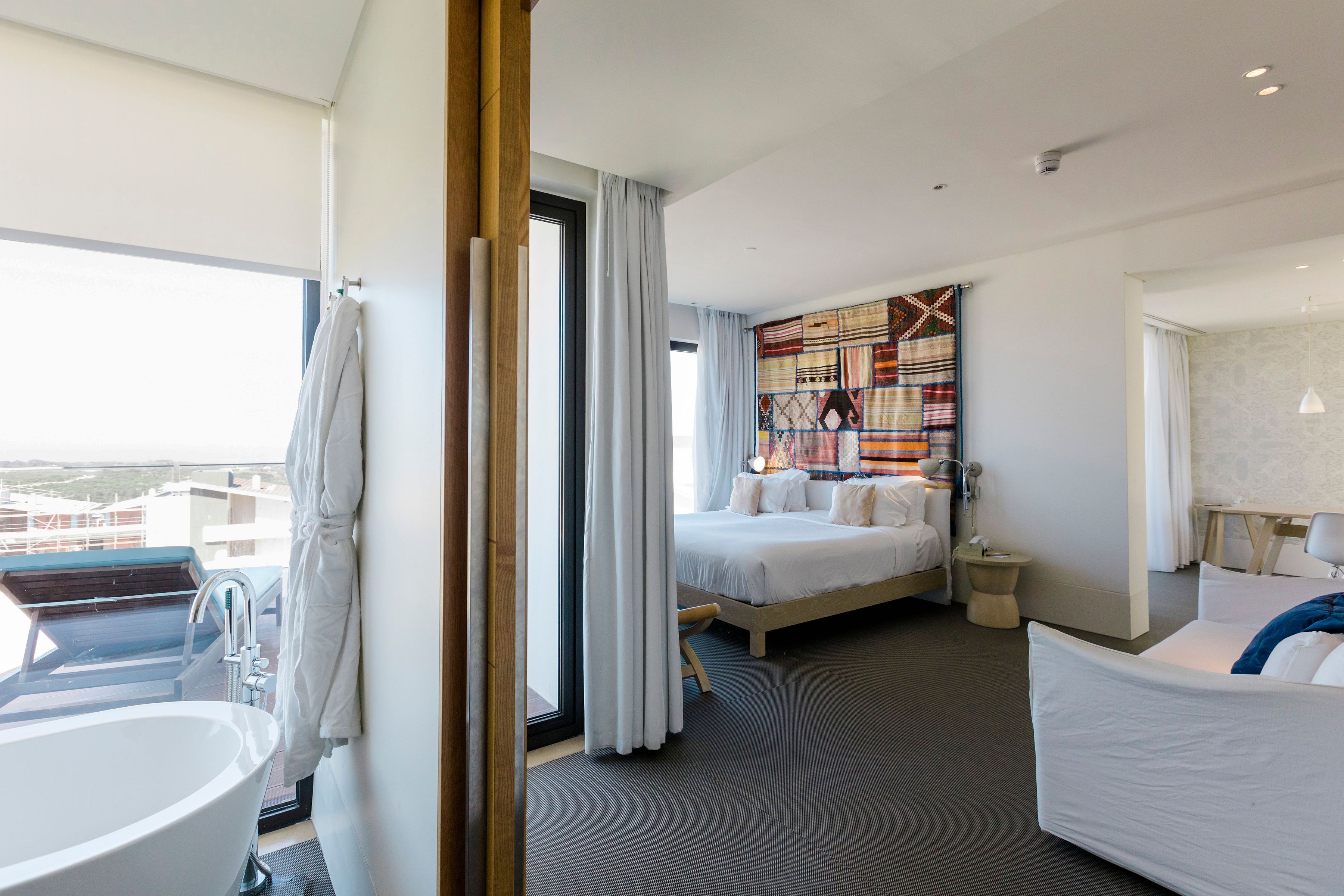 Quarto de hotel com uma cama grande, banheiro com banheira e vista para a cidade.