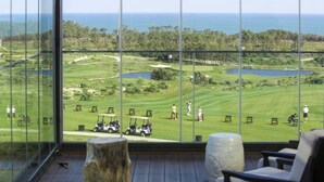 Vista de um quarto com amplas janelas para um campo de golfe com água e árvores.