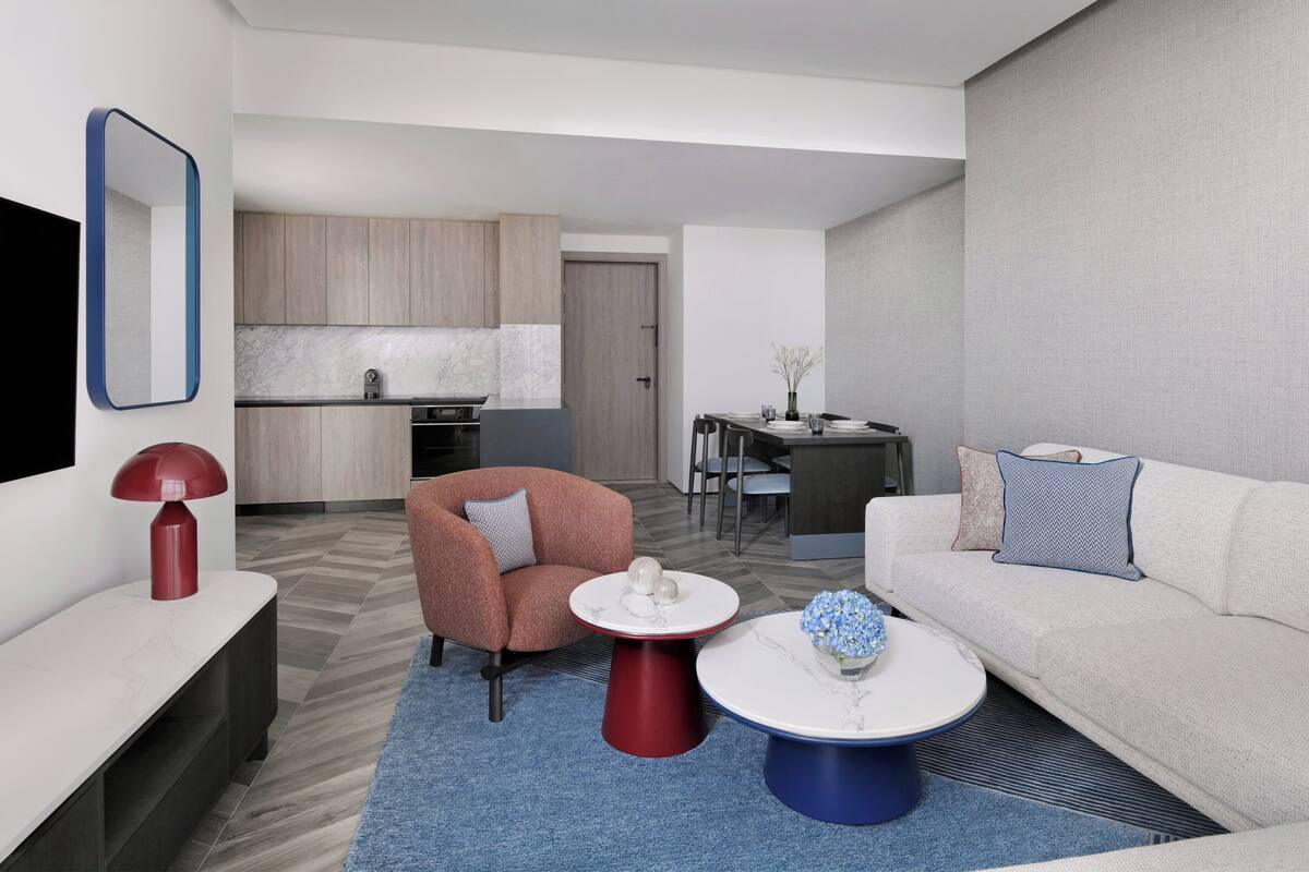 Uma sala de estar moderna com sofá, poltrona, mesa de centro e um espaço de jantar com mesa e cadeiras.