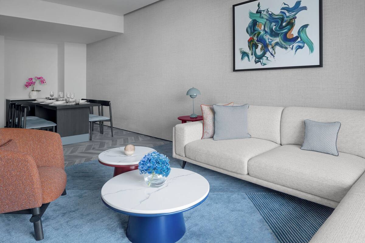 Uma sala de estar moderna com sofá, mesa de centro e área de jantar com cadeiras e mesa.