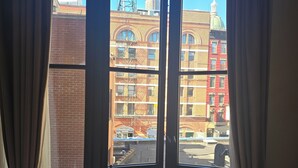 Quarto de hotel com uma grande janela que oferece vista para a paisagem urbana, incluindo edifícios e um tanque de água.