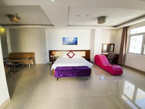 Um quarto de hotel espaçoso com uma cama grande, um sofá, uma poltrona e uma mesa de trabalho.