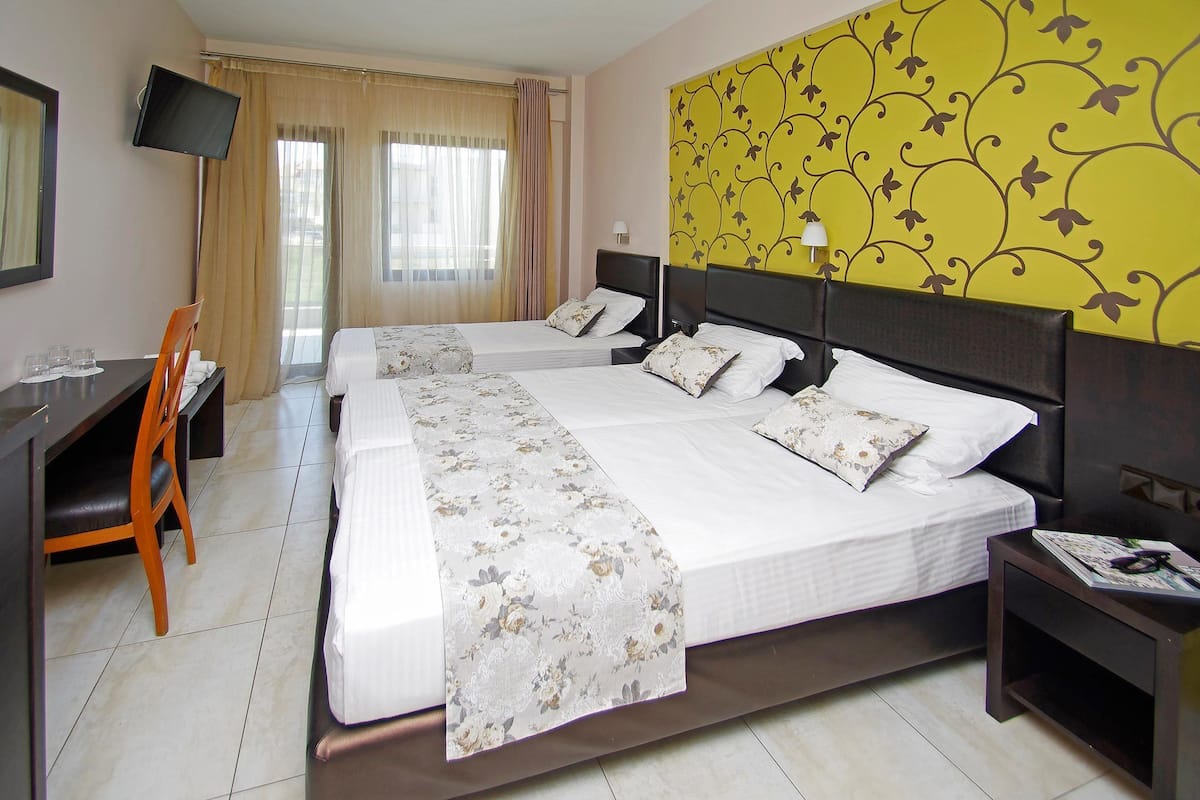 Quarto de hotel com duas camas, uma escrivaninha e uma televisão.