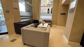 Um saguão com assentos, uma mesa de recepção e vista para a rua.