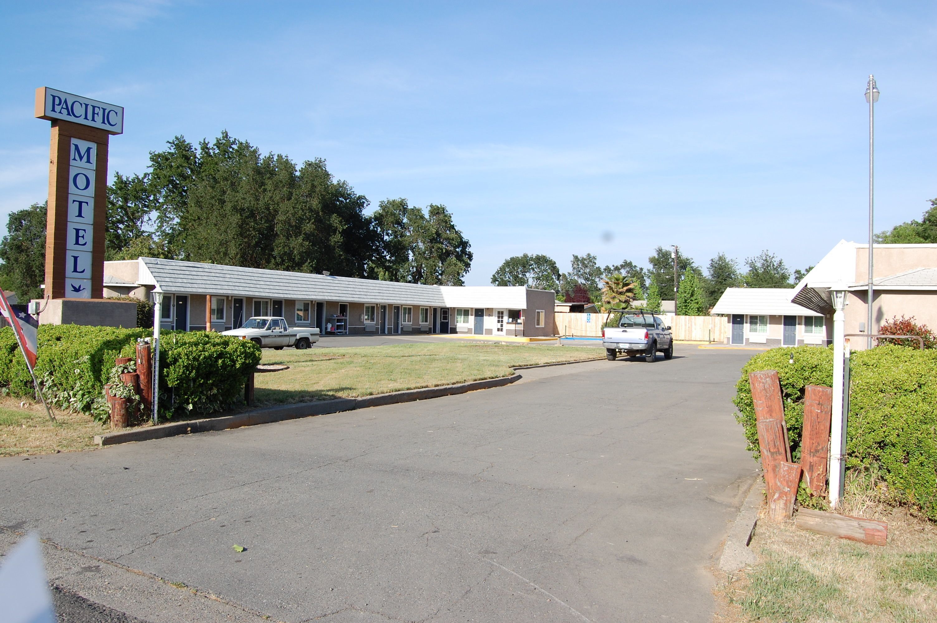 Um Motel Pacifico com estrutura em um único andar, área de estacionamento coberta e um gramado.
