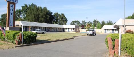 Um Motel Pacifico com estrutura em um único andar, área de estacionamento coberta e um gramado.