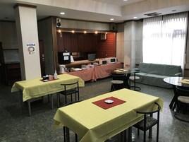Quarto de hotel com área de refeições, sofá e cozinha compacta.