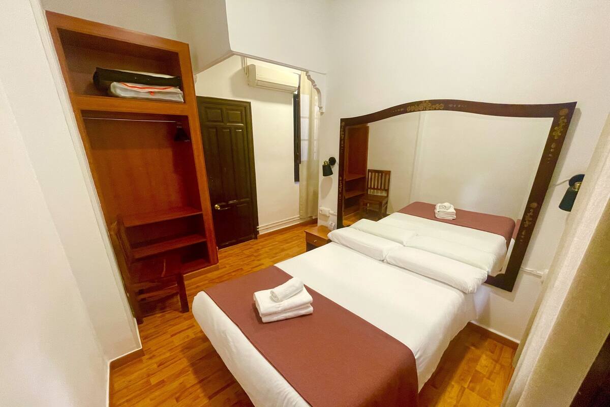 Quarto de hotel com cama, guarda-roupa de madeira, espelho e porta.