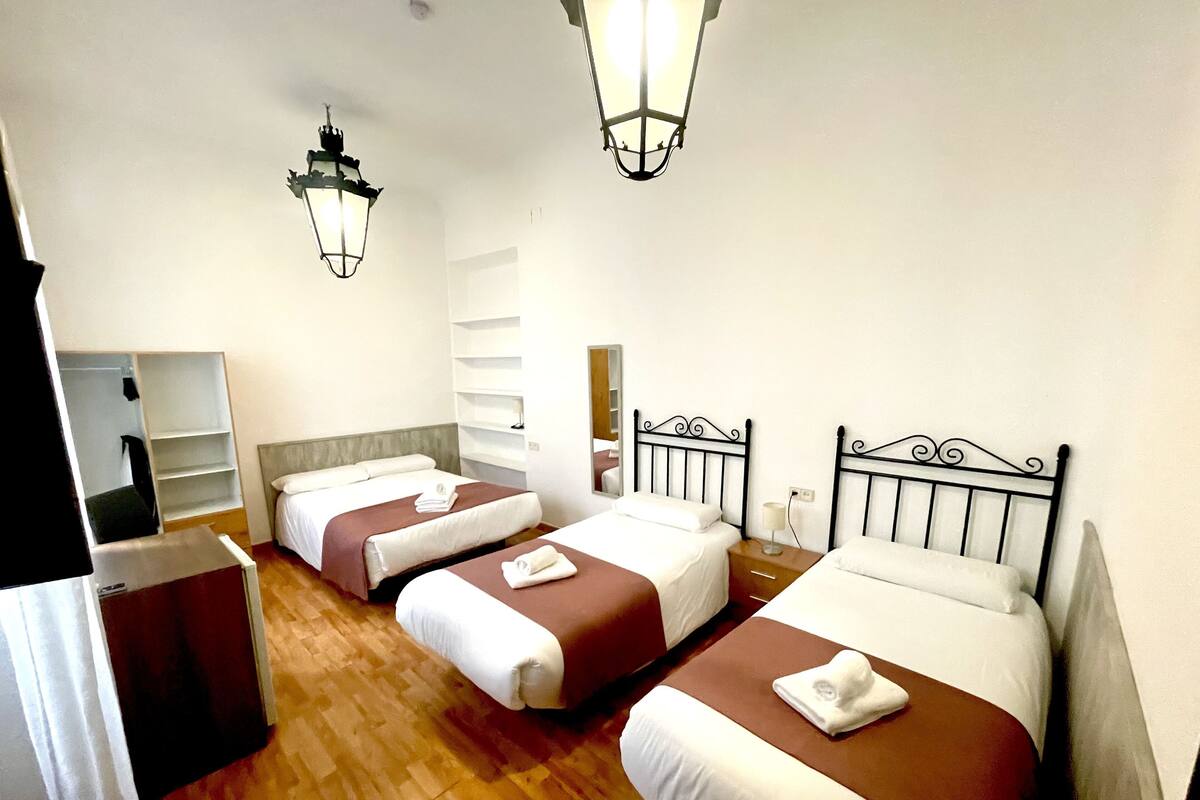 Quarto de hotel com duas camas, um guarda-roupa e um espelho.