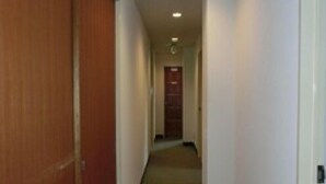 Um corredor estreito com portas de madeira de um lado e paredes brancas do outro.