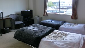 Quarto de hotel com duas camas, televisão, escrivaninha e janela com vista para o exterior.