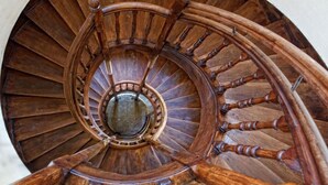Uma escada em caracol com degraus e balaústres de madeira.