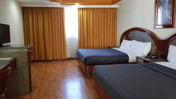 Quarto de hotel com duas camas, piso de madeira, uma mesa com televisão e um quadro na parede.