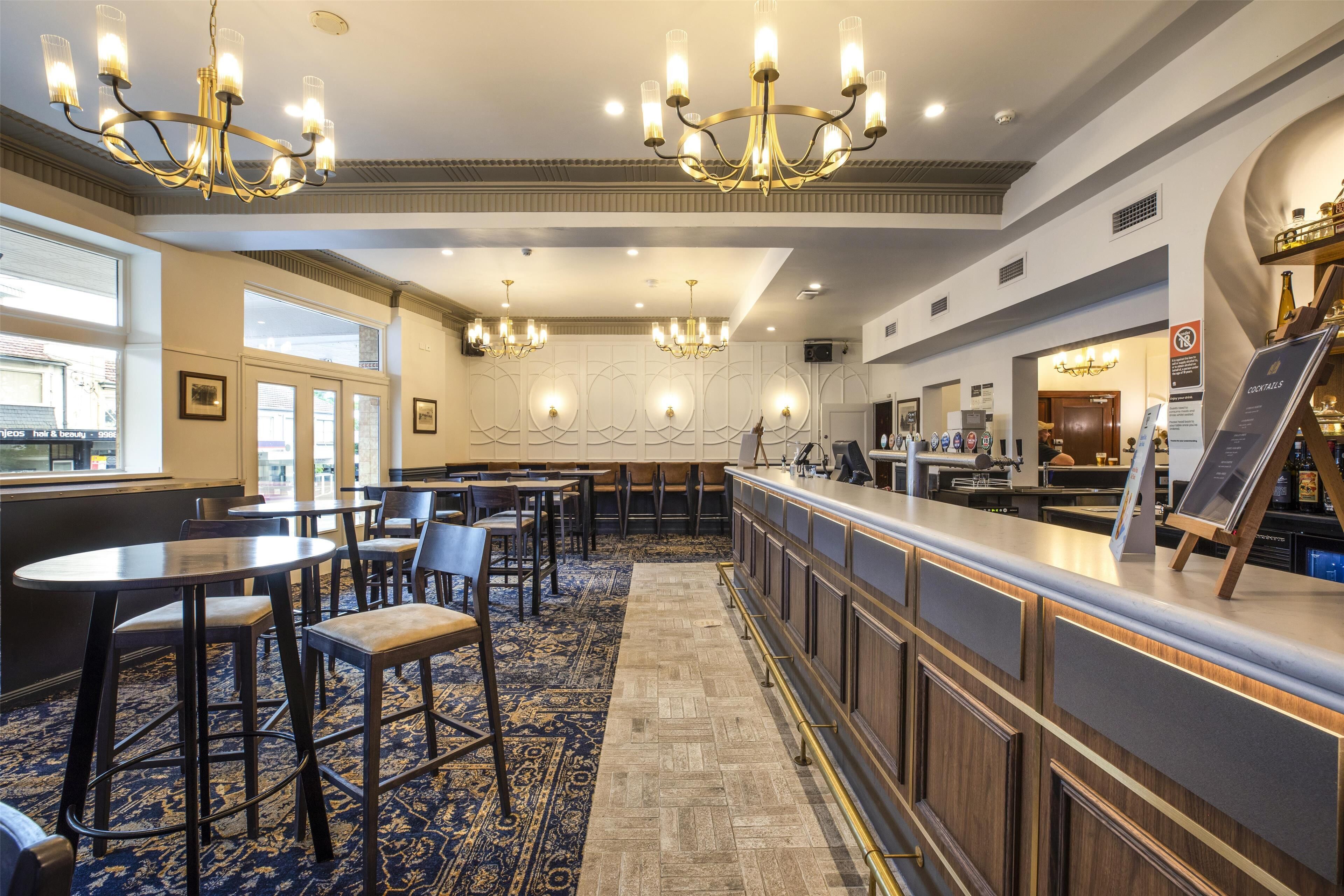 Um saguão de hotel com área de bar, assentos e um tapete estampado.