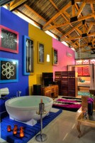 Quarto com uma banheira grande, vigas de madeira no teto e paredes coloridas.