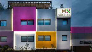 Hotel com vários andares e fachada moderna com painéis de cores distintas.