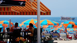 Um restaurante à beira-mar com mesas ao ar livre e guarda-sóis.