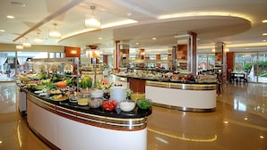 Uma área de buffet com diversas estações de comida e um espaço de refeições com mesas e cadeiras.