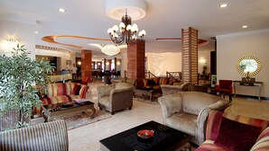 Um hall amplo com várias áreas de estar, um lustre imponente e um balcão de recepção.
