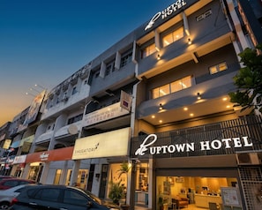 Um edifício de vários andares com um letreiro chamativo que diz 'UPTOWN HOTEL'.