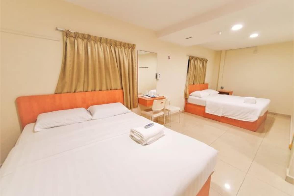 Quarto de hotel com duas camas, uma escrivaninha e uma cadeira.