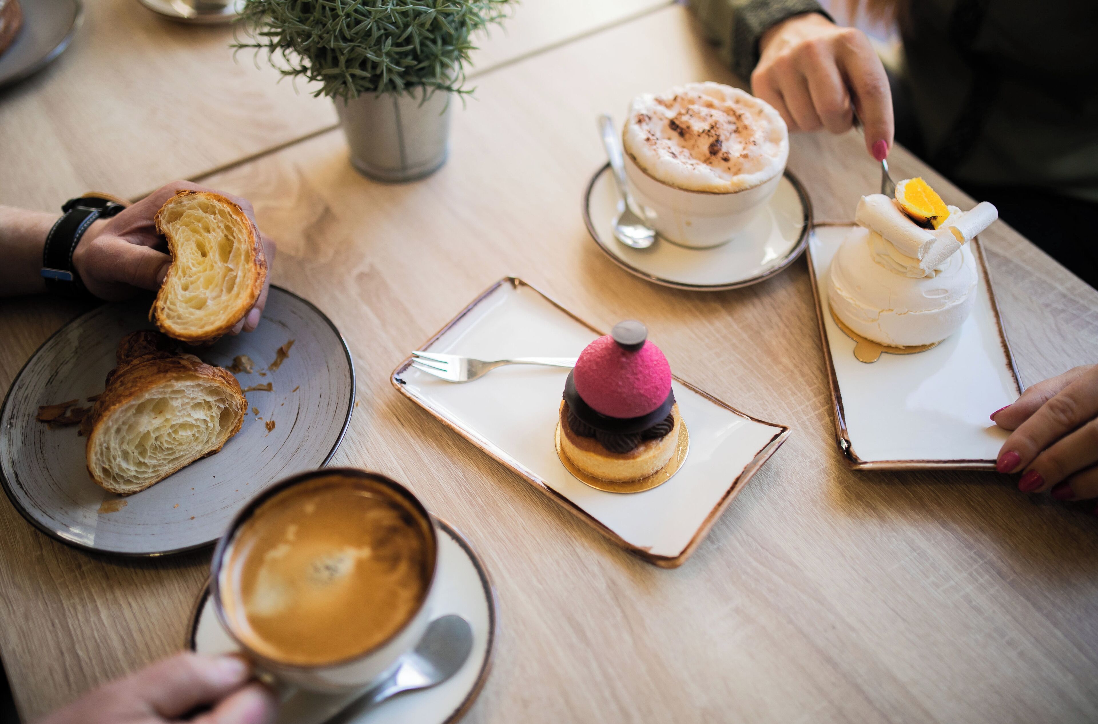 Uma mesa com doces, uma xícara de café e uma planta.