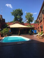 Uma área de piscina com espaço coberto para sentar e espreguiçadeiras.