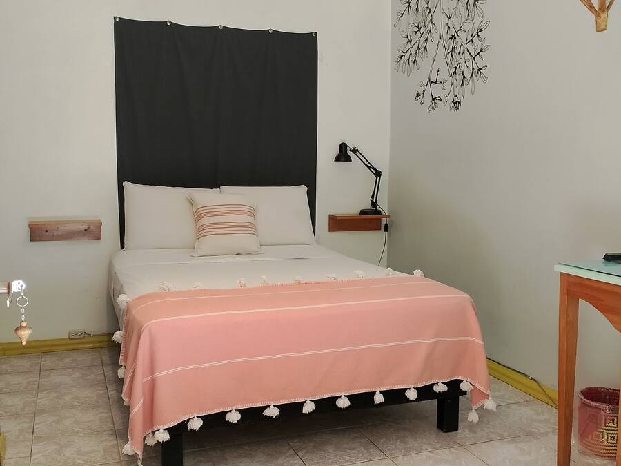 Quarto com cama, escrivaninha, luminária, obra de arte na parede e tapete.