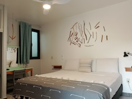 Quarto com cama, mesas de cabeceira, escrivaninha e espelho.