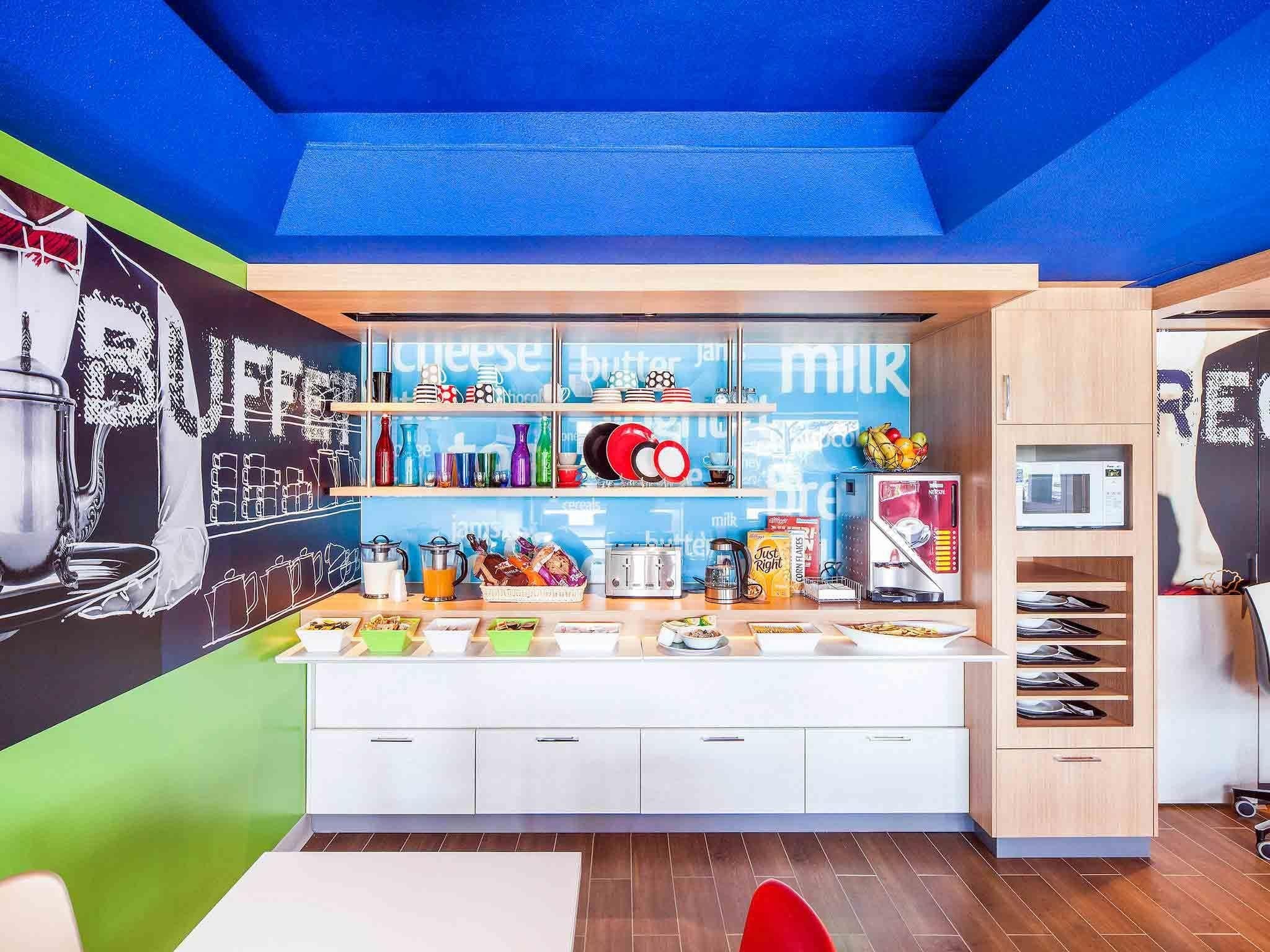 Uma cozinha moderna com teto azul, armários brancos e diversos eletrodomésticos e utensílios.