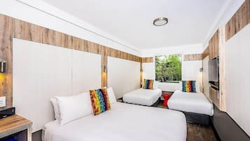 Quarto de hotel com uma cama grande, televisão e janela com vista para o verde.
