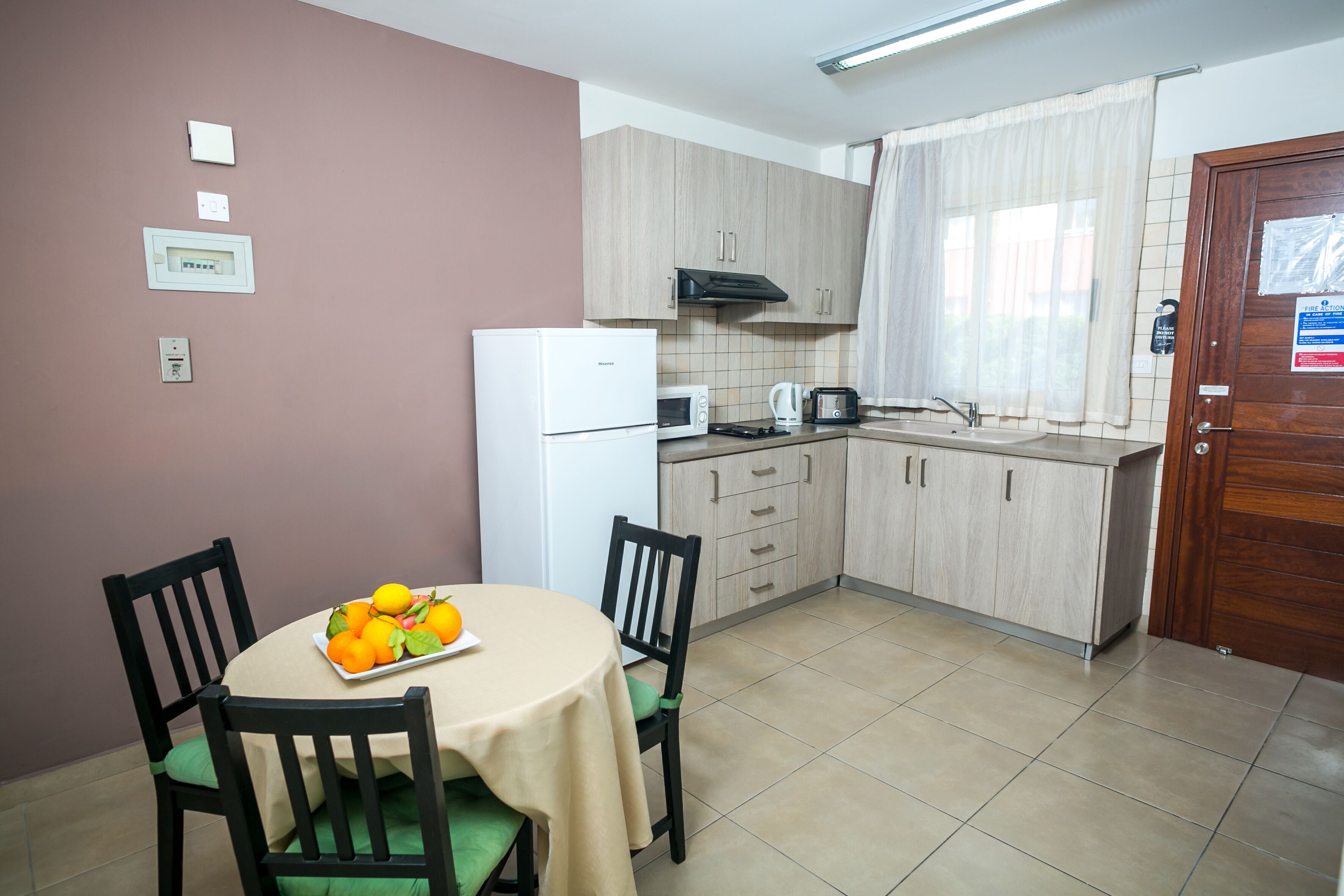 Cozinha compacta com área de jantar, equipada com geladeira, micro-ondas e chaleira.