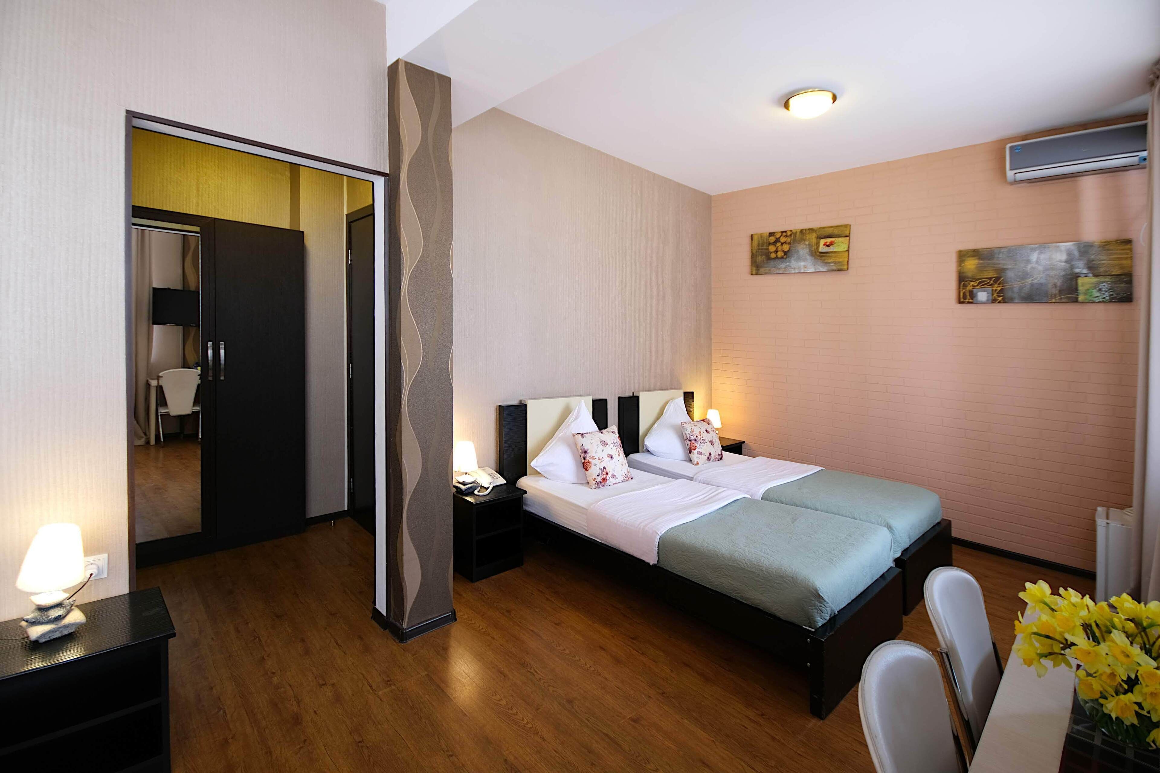 Quarto de hotel com cama, mesas de cabeceira, escrivaninha com luminária e uma cadeira.