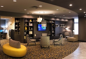 Um lobby moderno com área de estar em curva, televisão na parede e parede de destaque em pedra.
