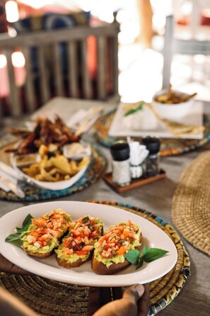 Uma mesa com vários pratos, incluindo uma travessa de bruschetta e outros alimentos.