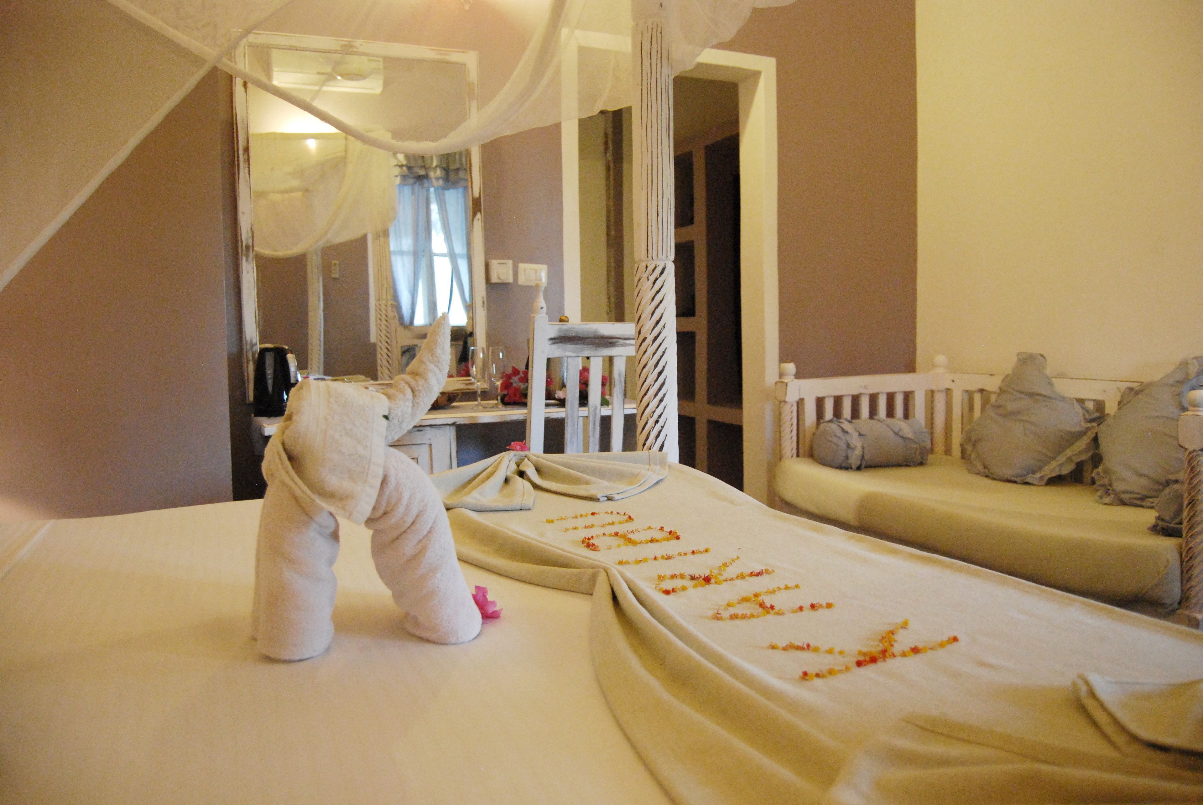 Quarto de hotel com uma cama, uma pequena escrivaninha, uma cadeira e um berço branco.