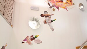 Uma escadaria com uma parede decorada com ilustrações de pássaros e uma pintura.