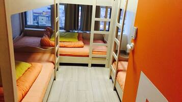 Quarto com beliche, janela, soalho de madeira e paredes laranja.