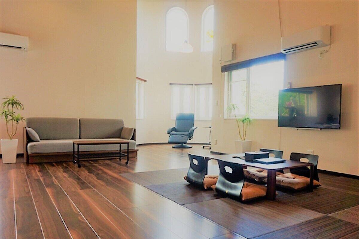 Uma sala de estar moderna com um sofá, cadeiras, uma TV e uma mesa com laptops.