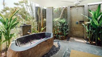 Uma área de spa com uma banheira independente, um ventilador de teto e uma parede de pedra.