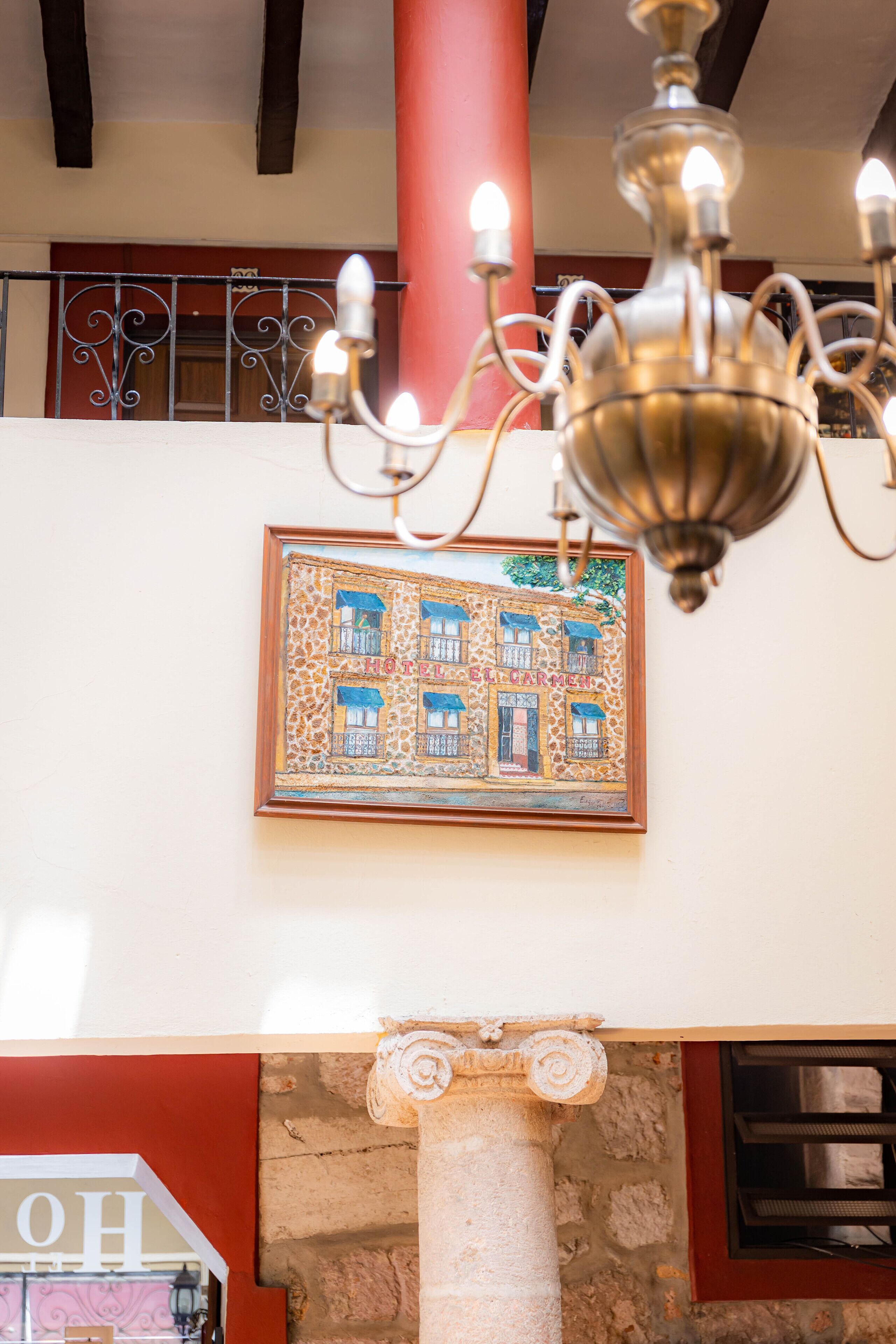 Um candelabro, uma obra de arte emoldurada retratando um edifício e uma coluna.