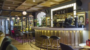 Uma área de bar com banquetas, balcão e um pinheiro de Natal.