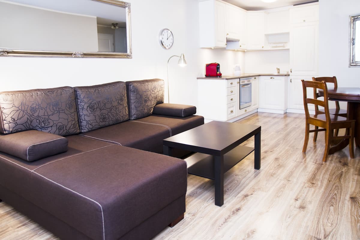 Uma sala de estar moderna com um sofá marrom, uma mesa de centro e uma área de jantar com cadeiras e mesa de madeira.