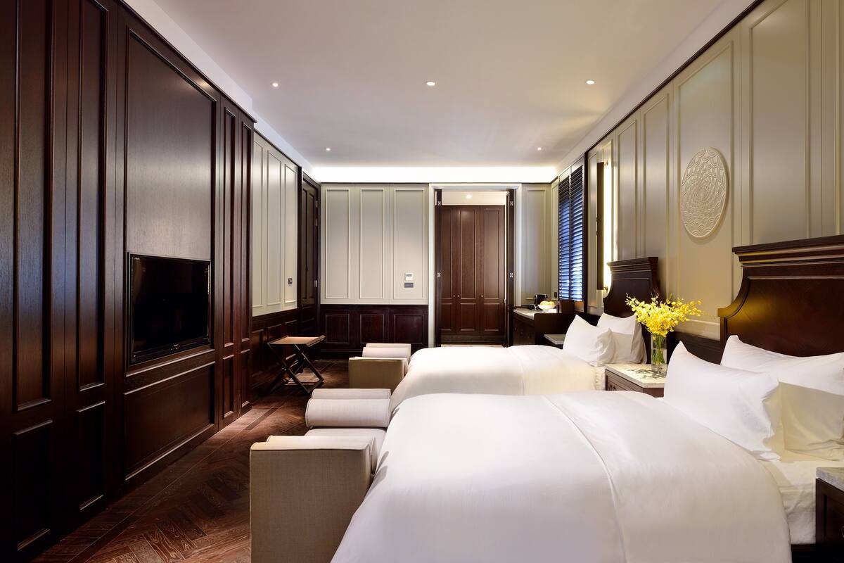 Quarto de hotel com uma cama grande, televisão, escrivaninha e banheiro visível por uma porta aberta.