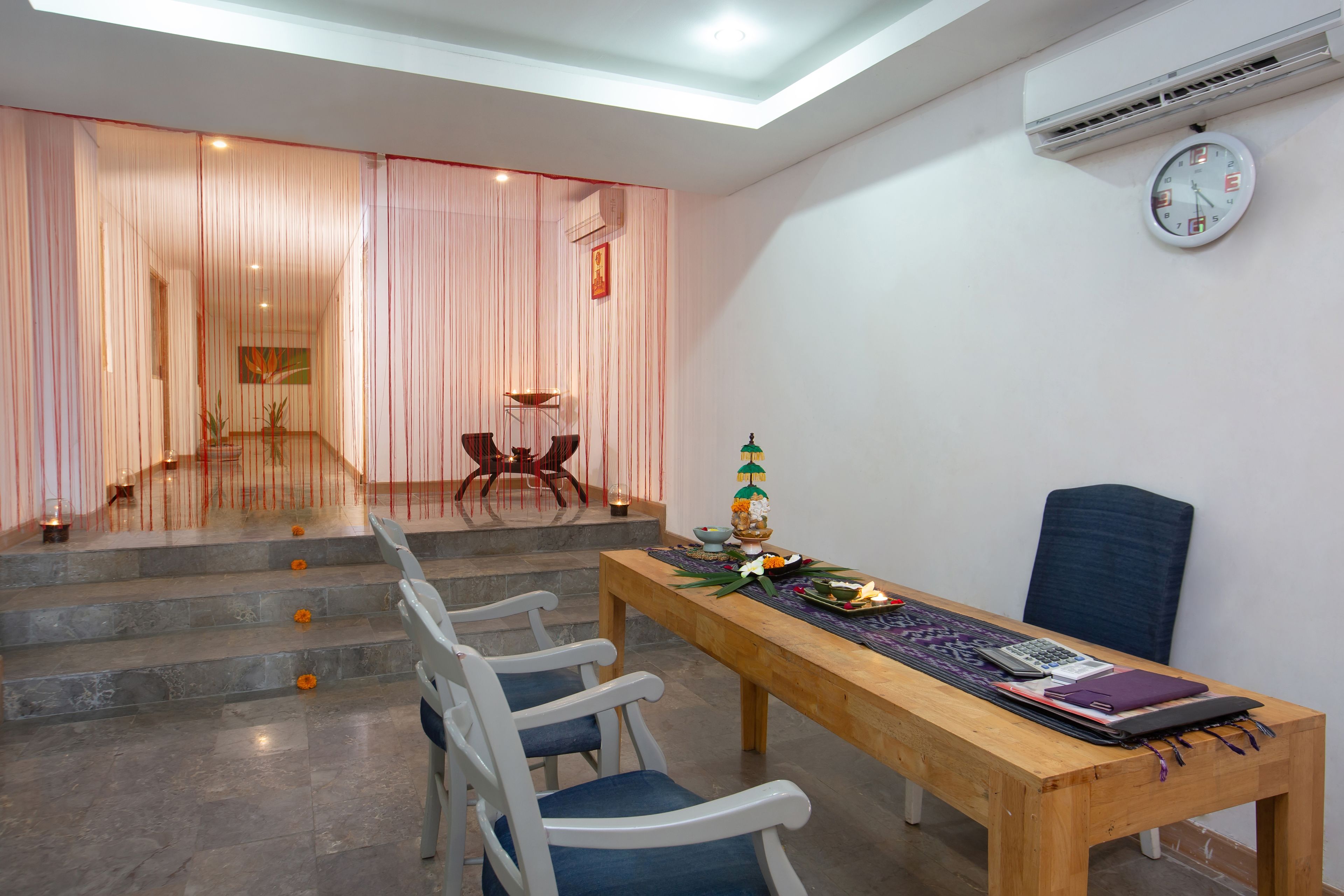 Uma área de refeições com uma mesa de madeira, cadeiras e um relógio na parede.